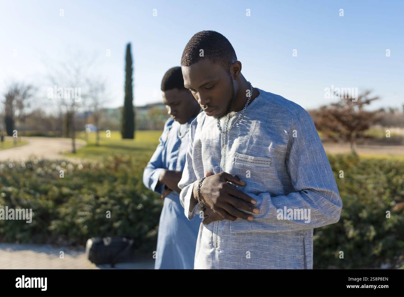 Two young senegalese men wearing traditional clothing are praying ...