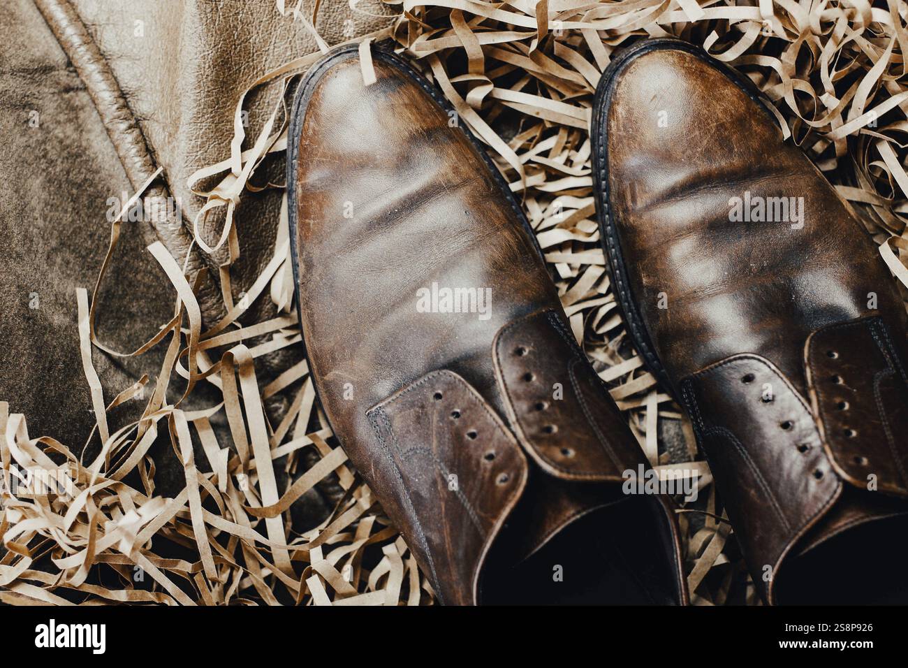 Pair of brown leather shoes on shredded paper, creating a rustic and ...