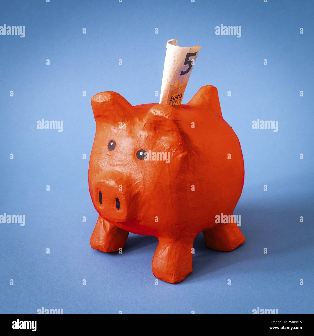 An image of a red papier mache piggy bank with 5 Euros Stock Photo - Alamy