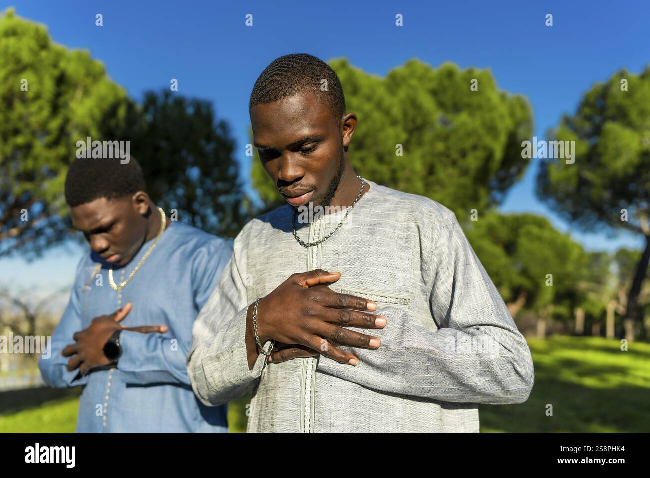 Two young senegalese men wearing traditional clothing are praying ...
