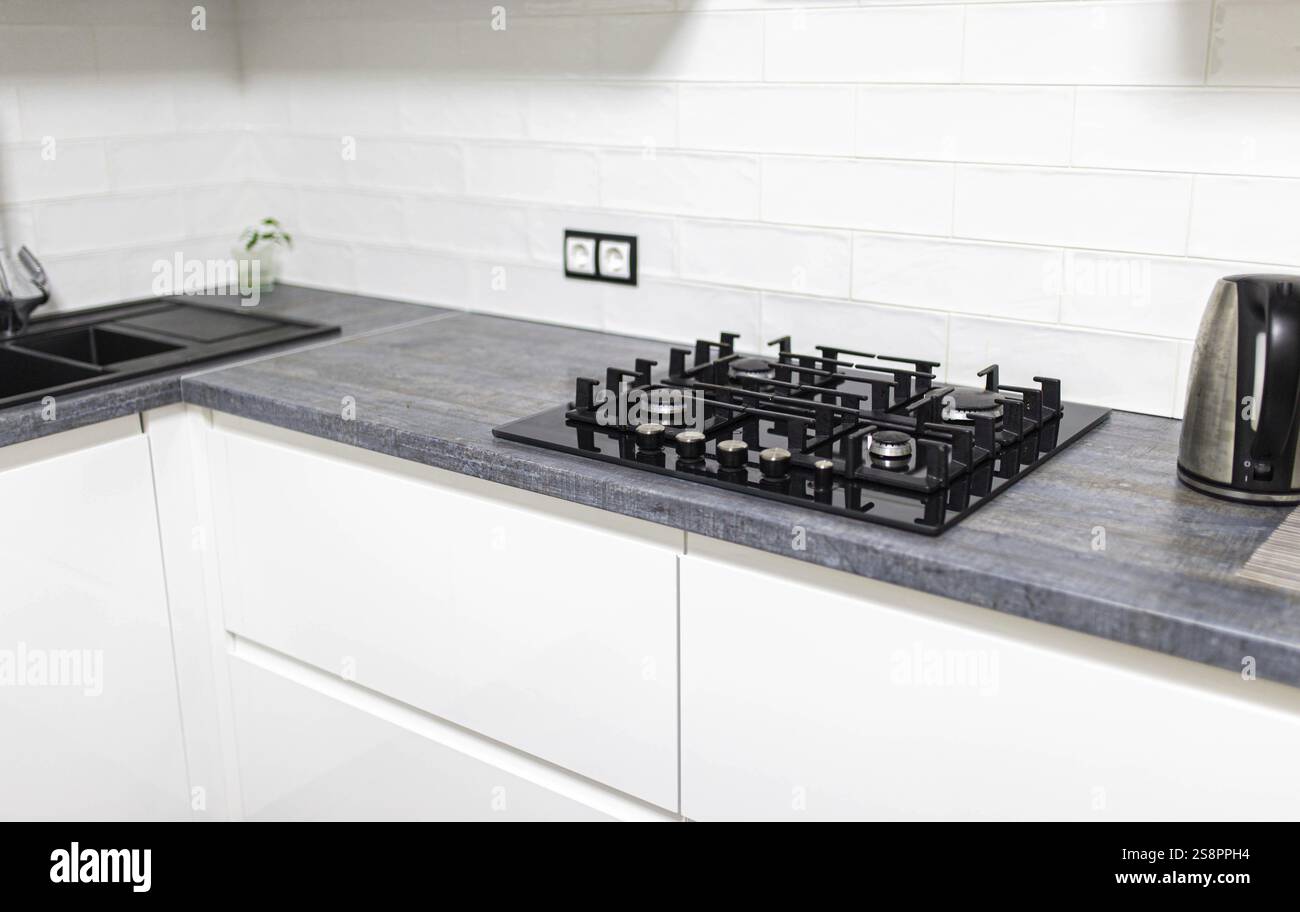 A modern kitchen with a gas stove and kettle on a countertop Stock ...