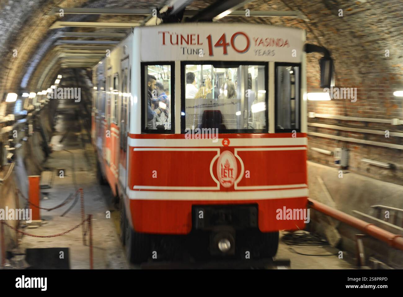 Rushing train in a historic brick tunnel, illuminated with industrial ...