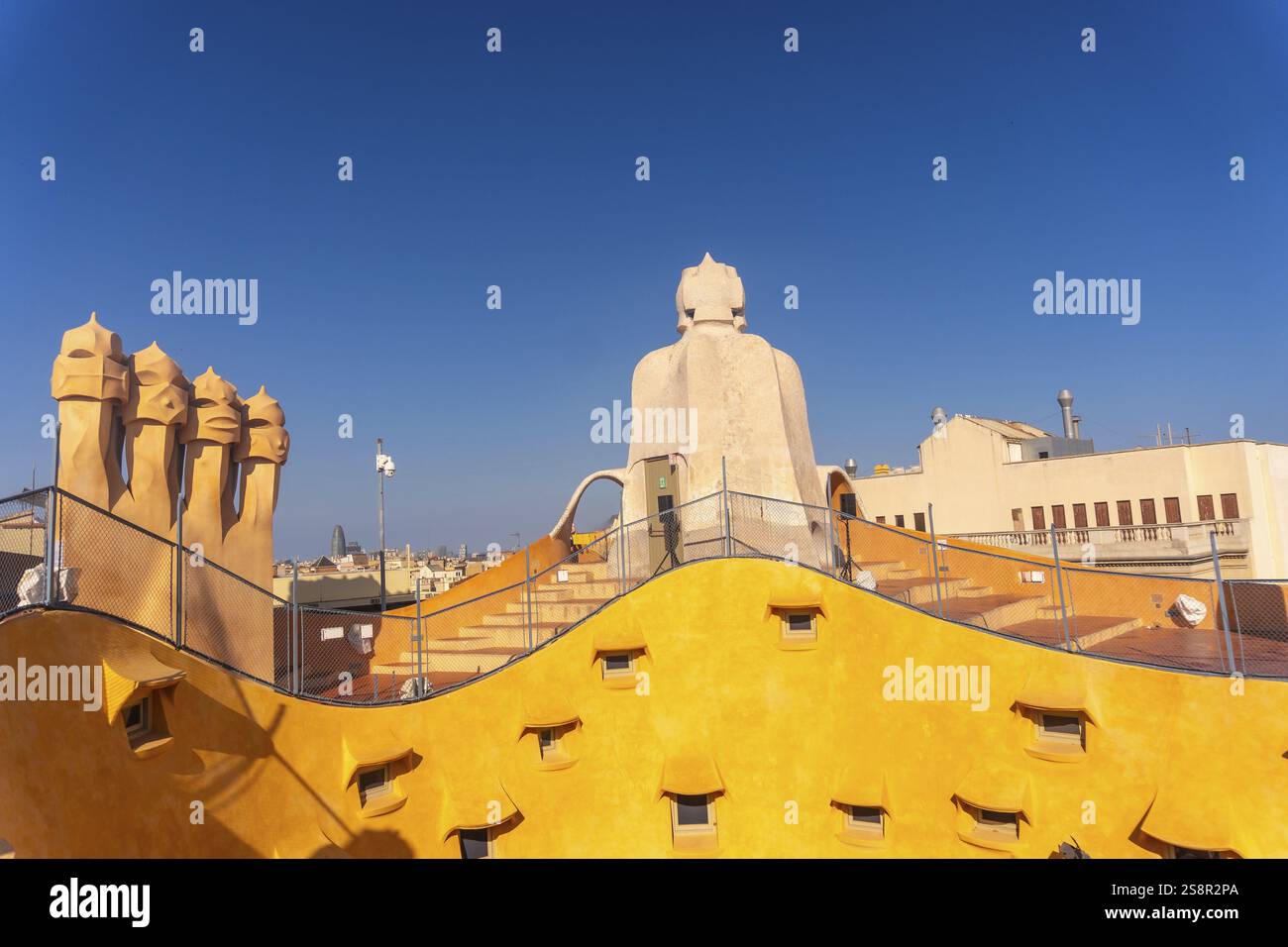 Bright yellow rooftop with unusual chimneys and staircase access under ...