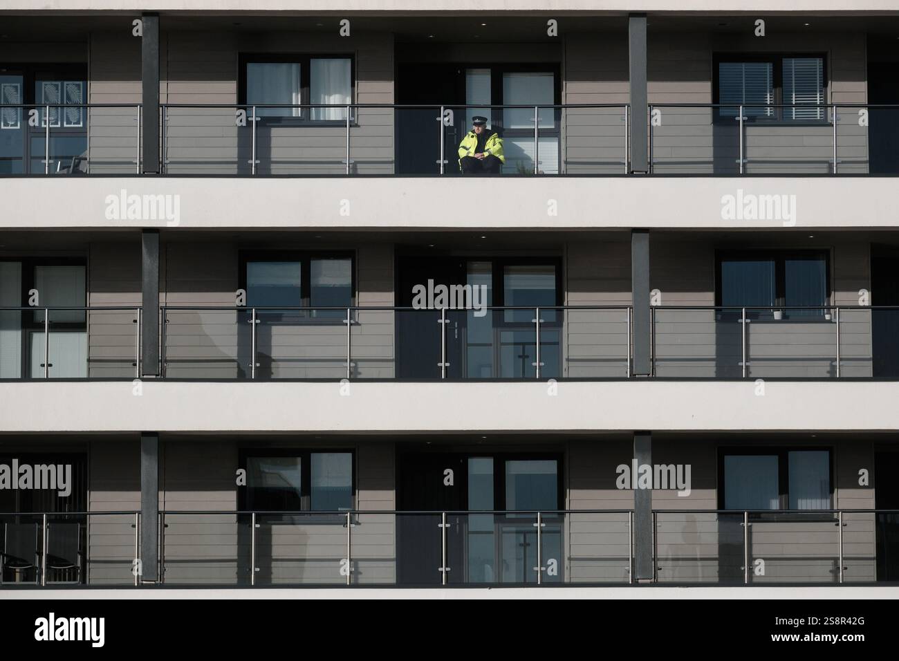 A police officer sits outside a block of flats at a scene in Plymouth ...