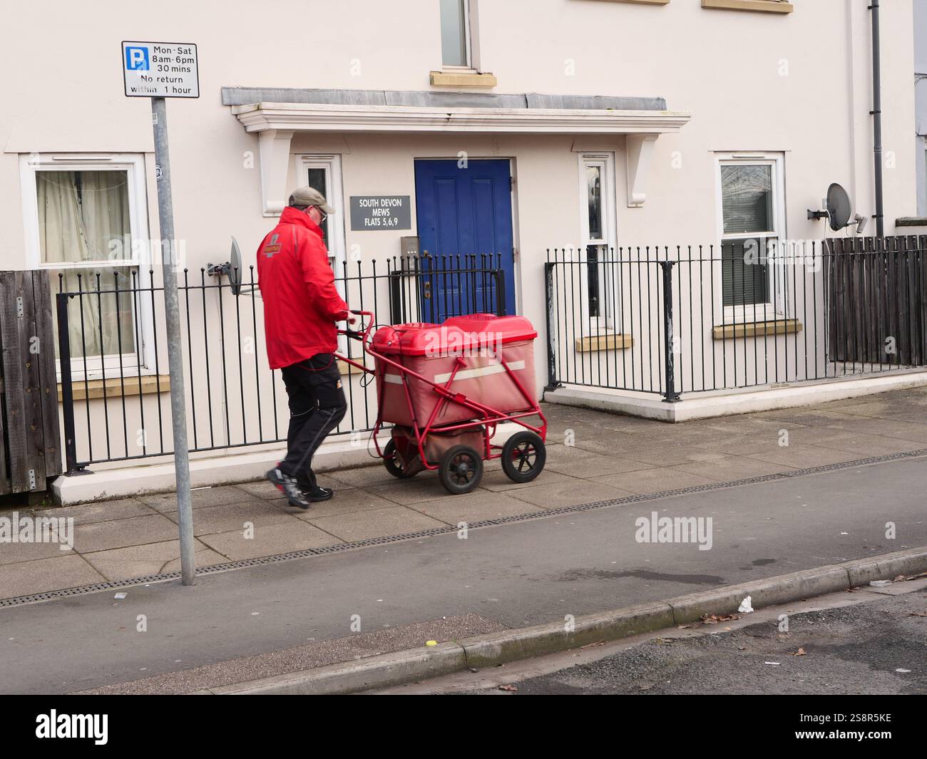 Royal Mail postman delivering letters on foot using a mail trolley ...