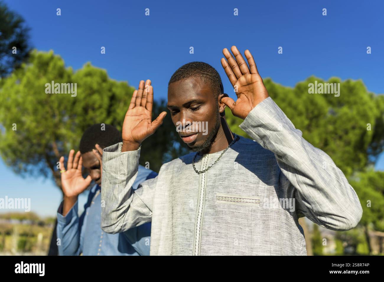 Two young senegalese men wearing traditional clothing are praying ...