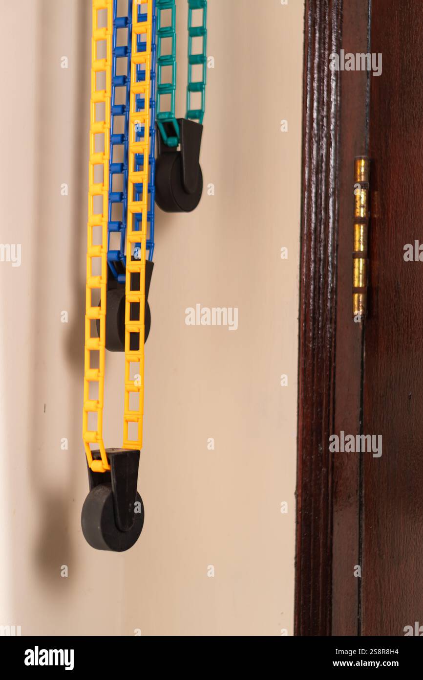 Three colorful plastic chains with wheels hanging against a wall next ...
