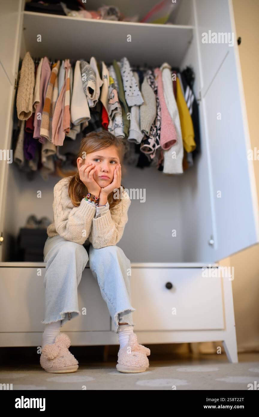 Girl is sitting close to her wardrobe with sad face and thinking what ...