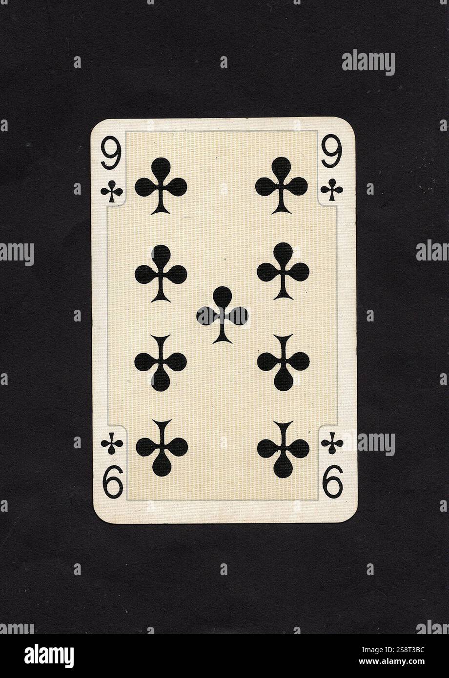 An antique nine of clubs playing card isolated on a black background ...