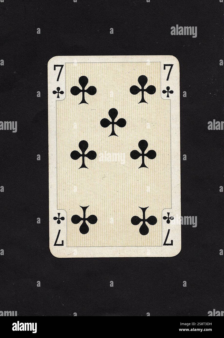 An antique seven of clubs playing card isolated on a black background ...
