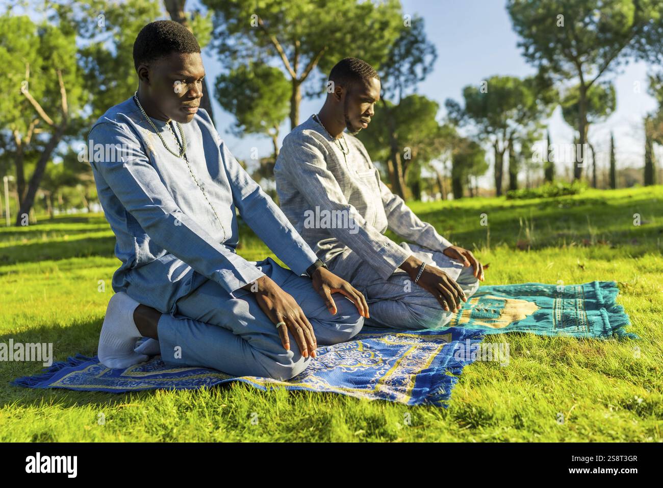 Two young senegalese men wearing traditional clothing are kneeling on ...