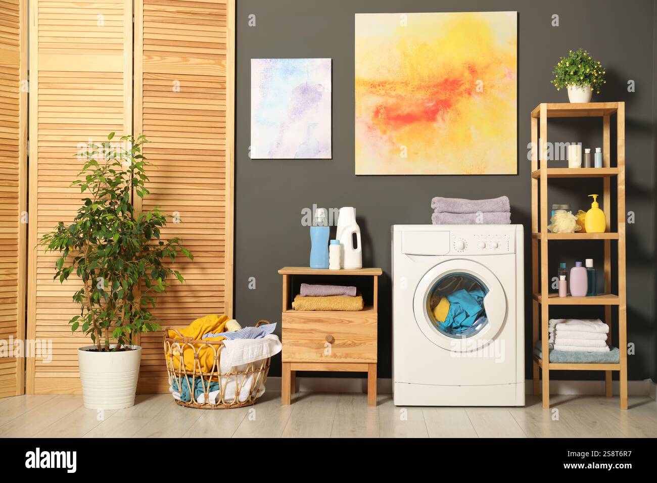 Washing machine, detergents and basket with laundry in room Stock Photo ...