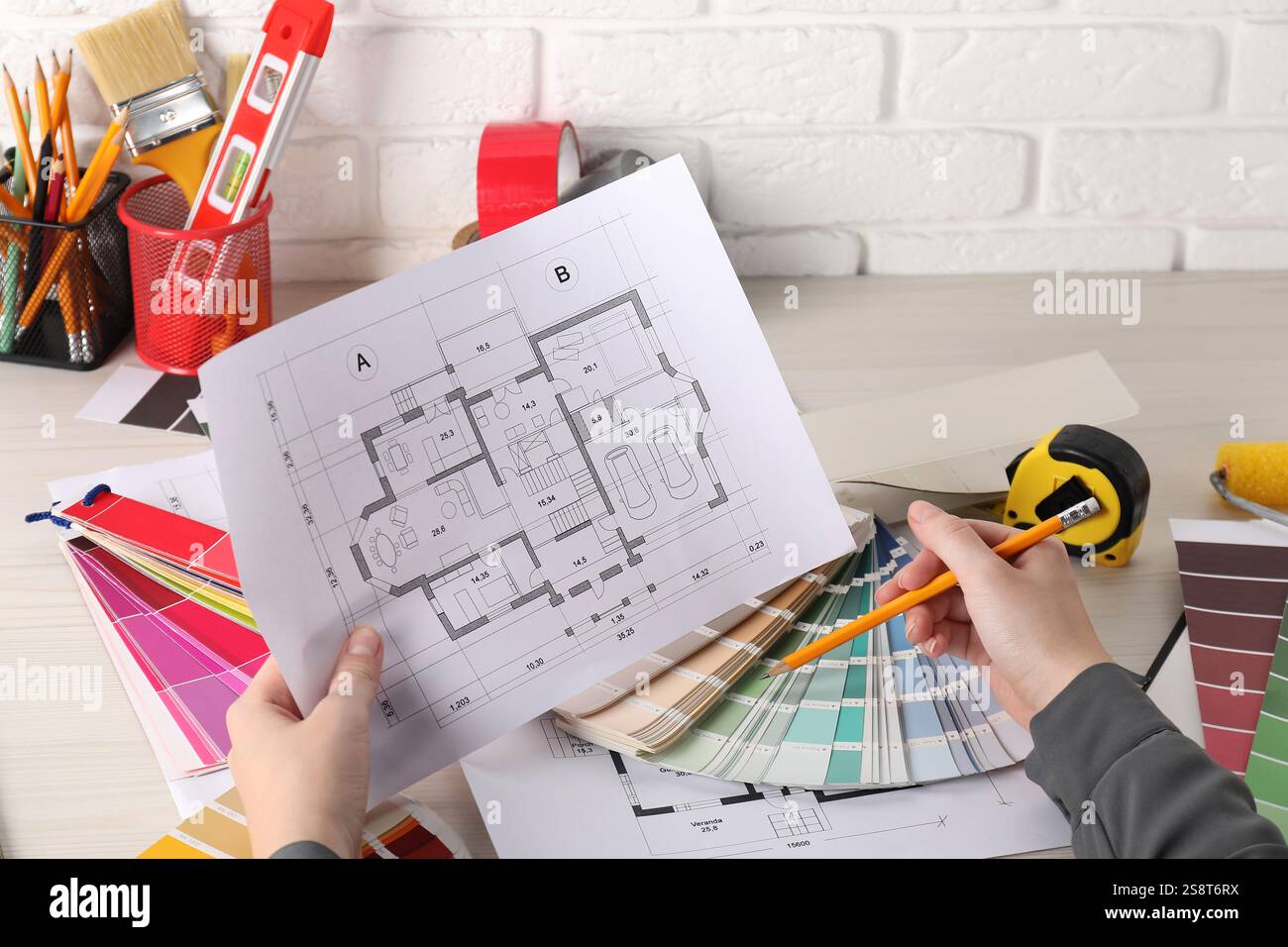 Designer working with house plan and color selection chart at white ...