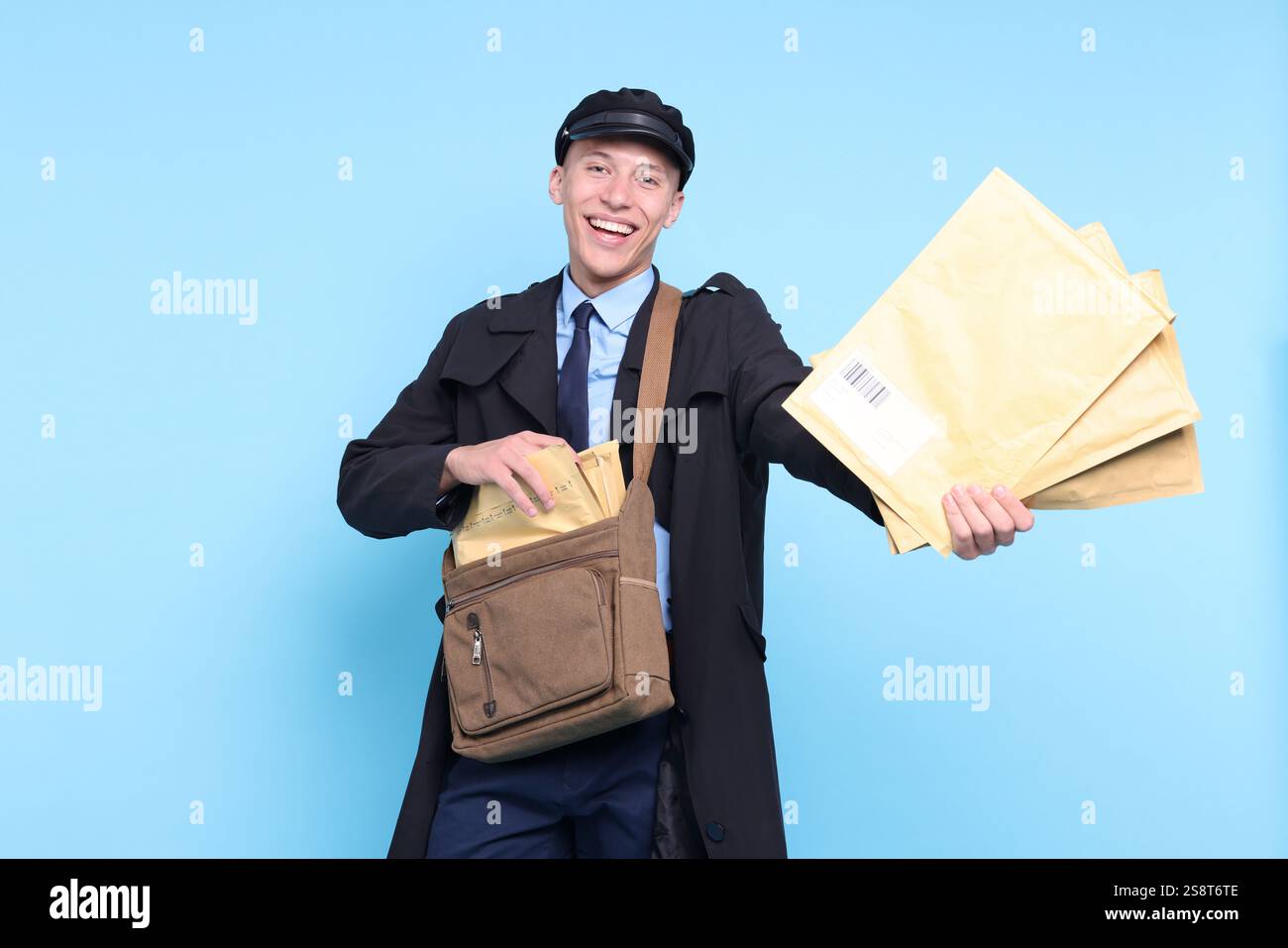 Happy postman with bag giving envelopes on light blue background Stock ...