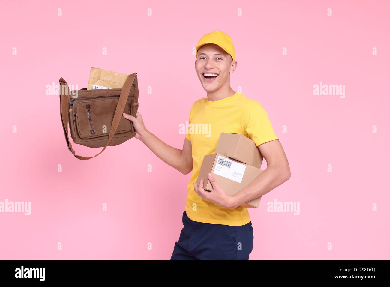 Happy postman with bag and parcels on pink background Stock Photo - Alamy
