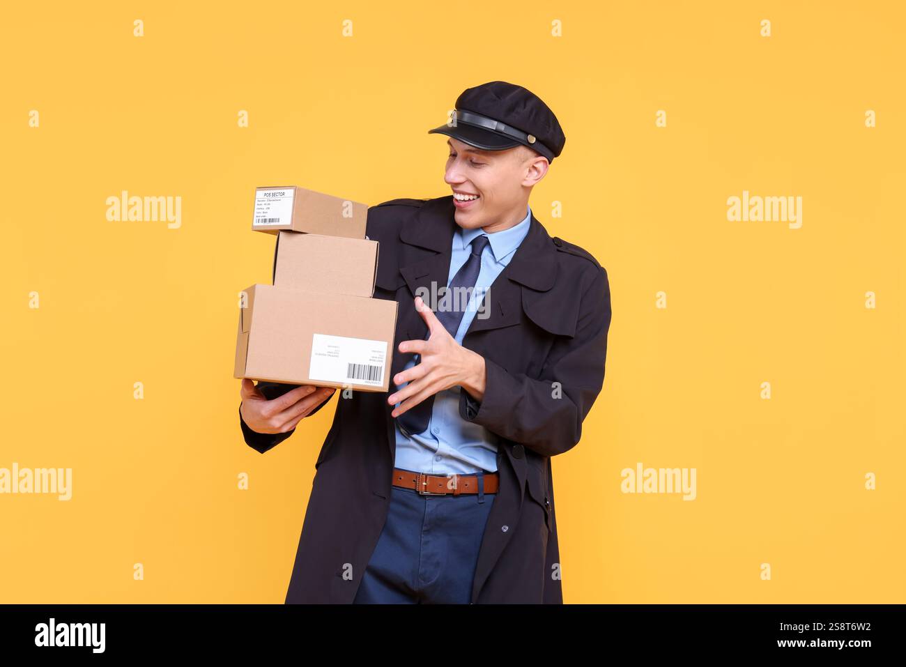 Happy postman with parcels on yellow background Stock Photo - Alamy