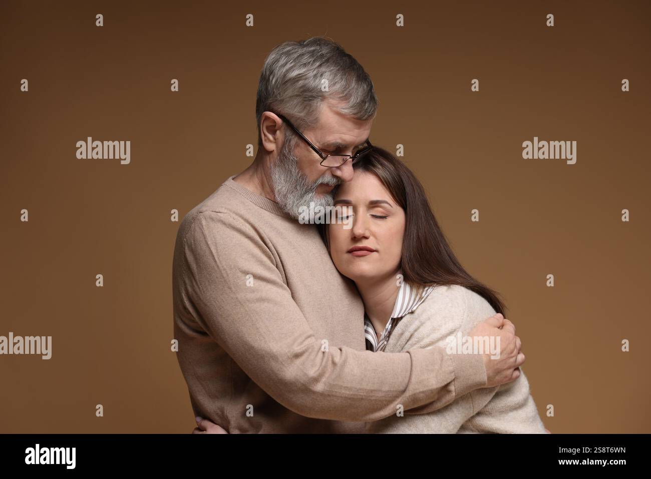 Father hugging his daughter on brown background Stock Photo - Alamy