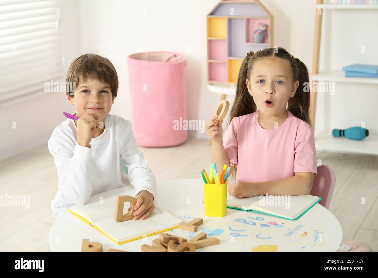 Little kids learning alphabet with wooden letters at white table ...