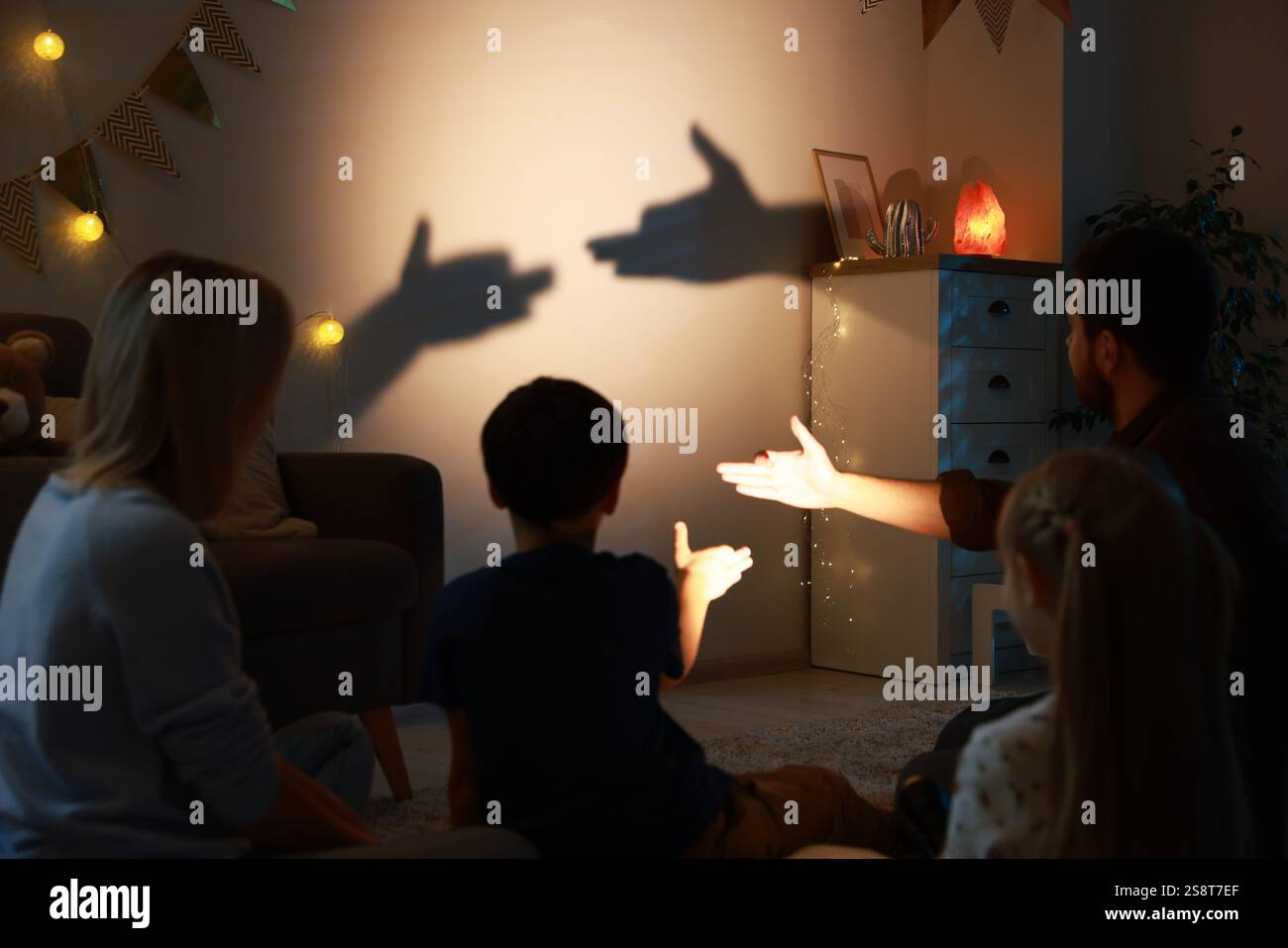 Shadow play. Father and his son making hand gestures like dogs on wall ...