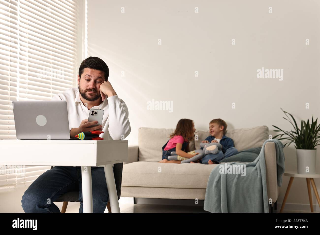 Naughty children disturbing their overwhelmed father at home Stock ...