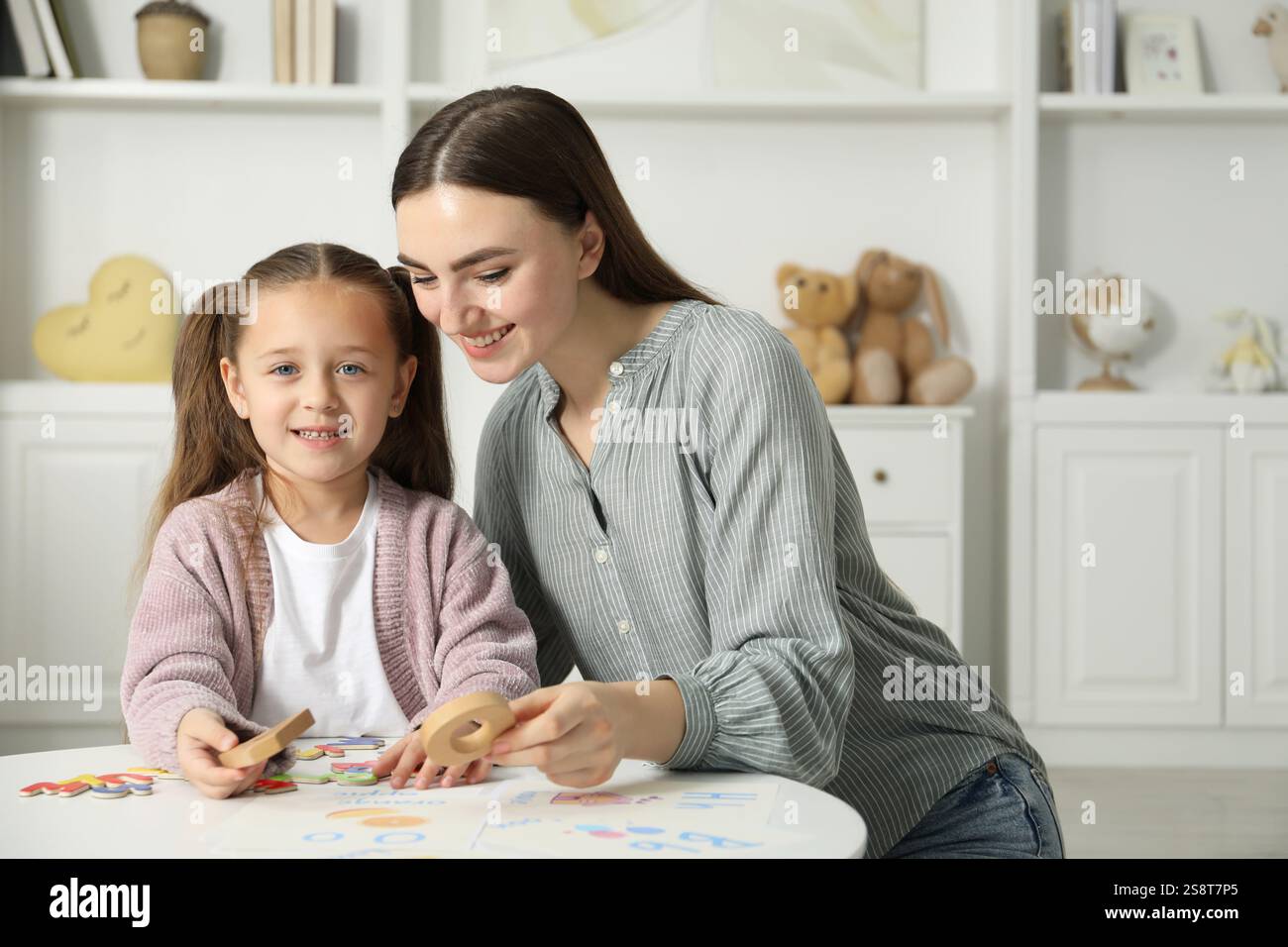 Speech therapist teaching little girl alphabet with different letters ...