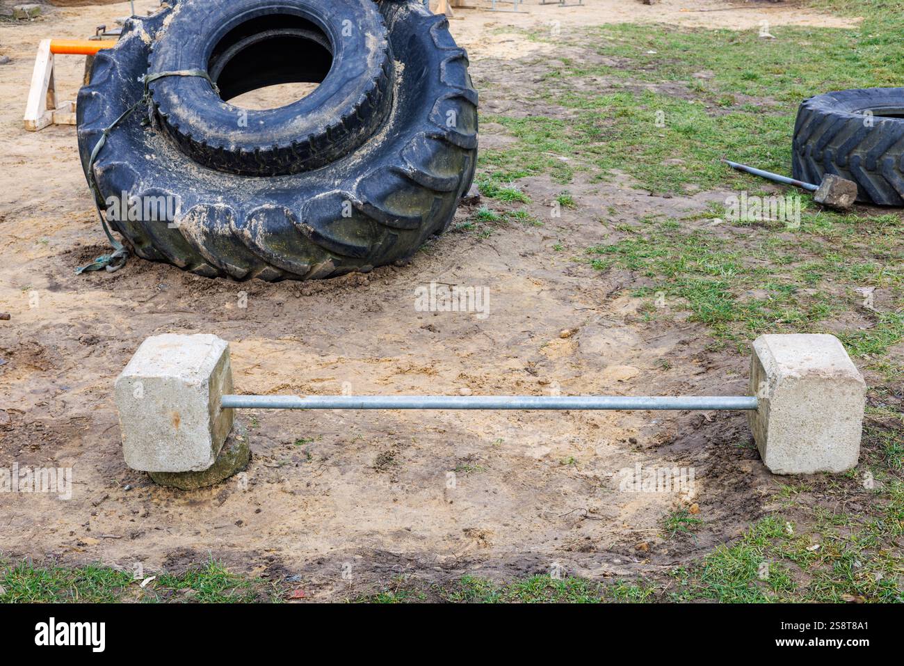 A barbell with concrete, square pancakes and a metal bar on the sand of ...