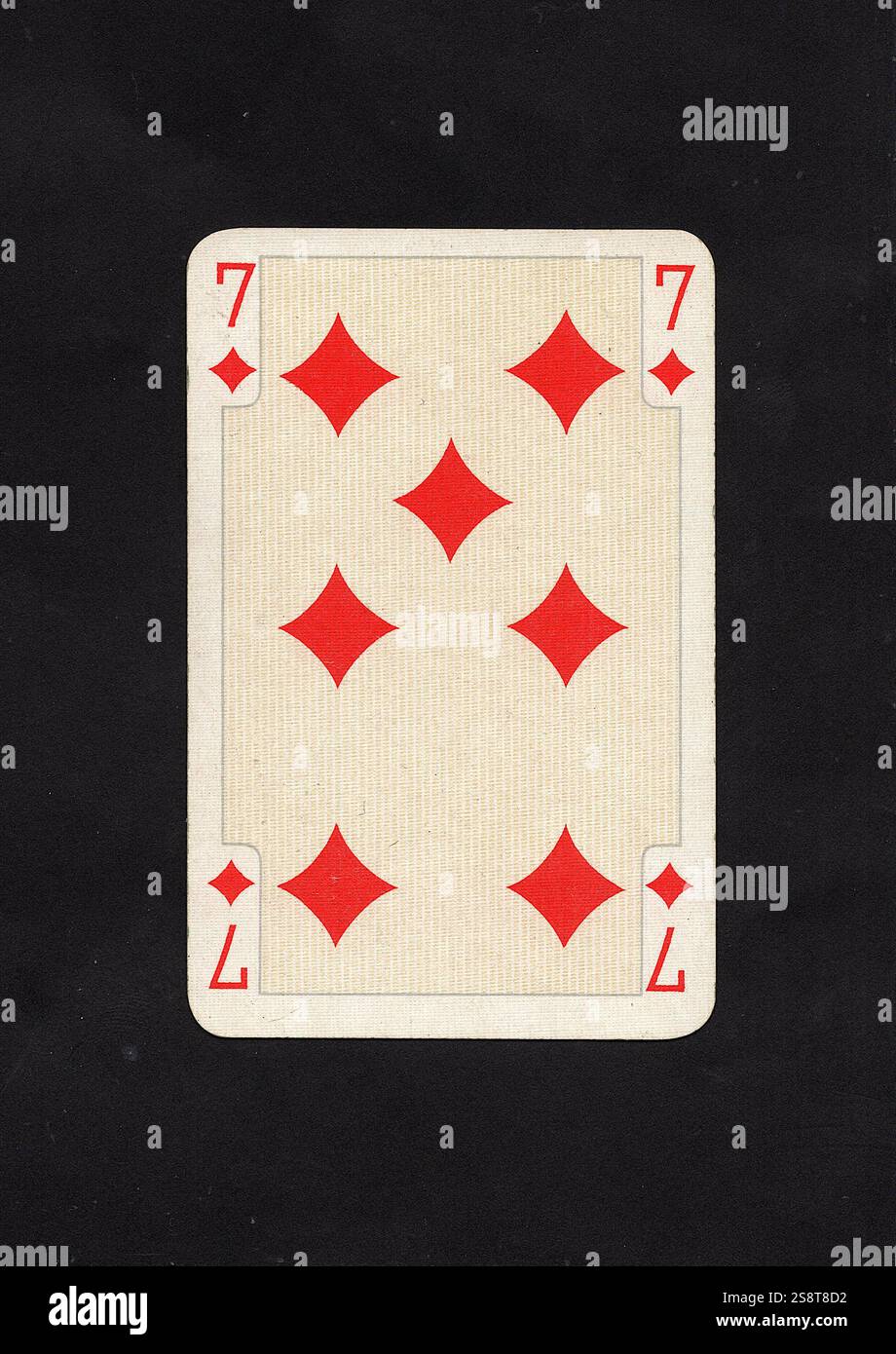 An antique seven of diamonds playing card isolated on a black ...