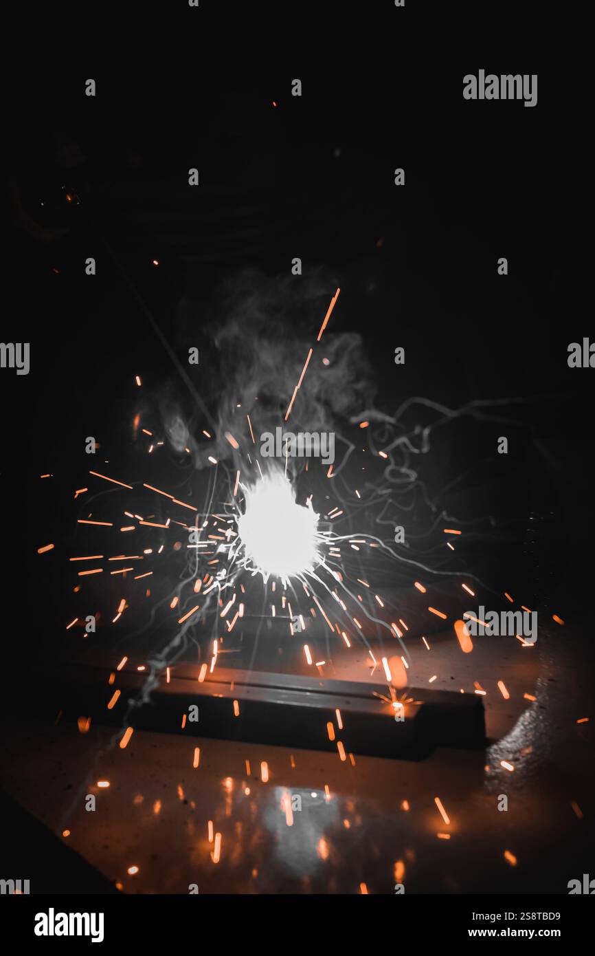 man joining iron profiles by welding Working in a dark environment with ...