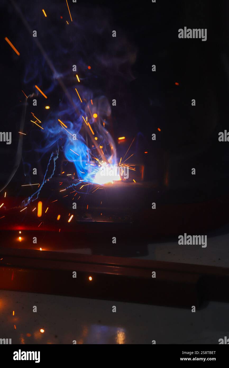 Welding sparks flying from metal as worker fuses steel with intense ...