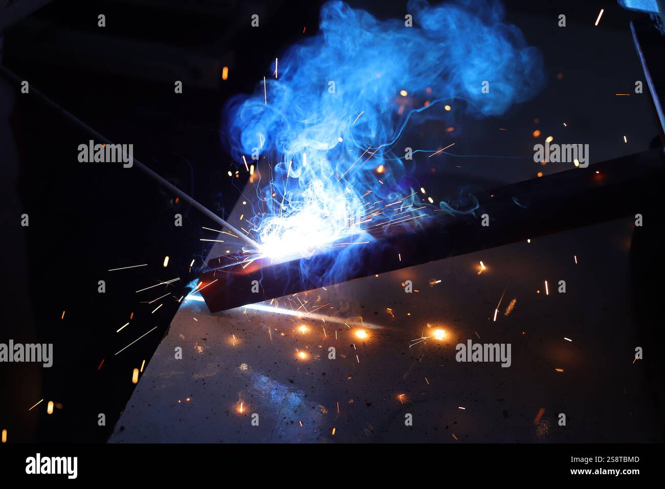 Welding sparks flying from metal as worker fuses steel with intense ...