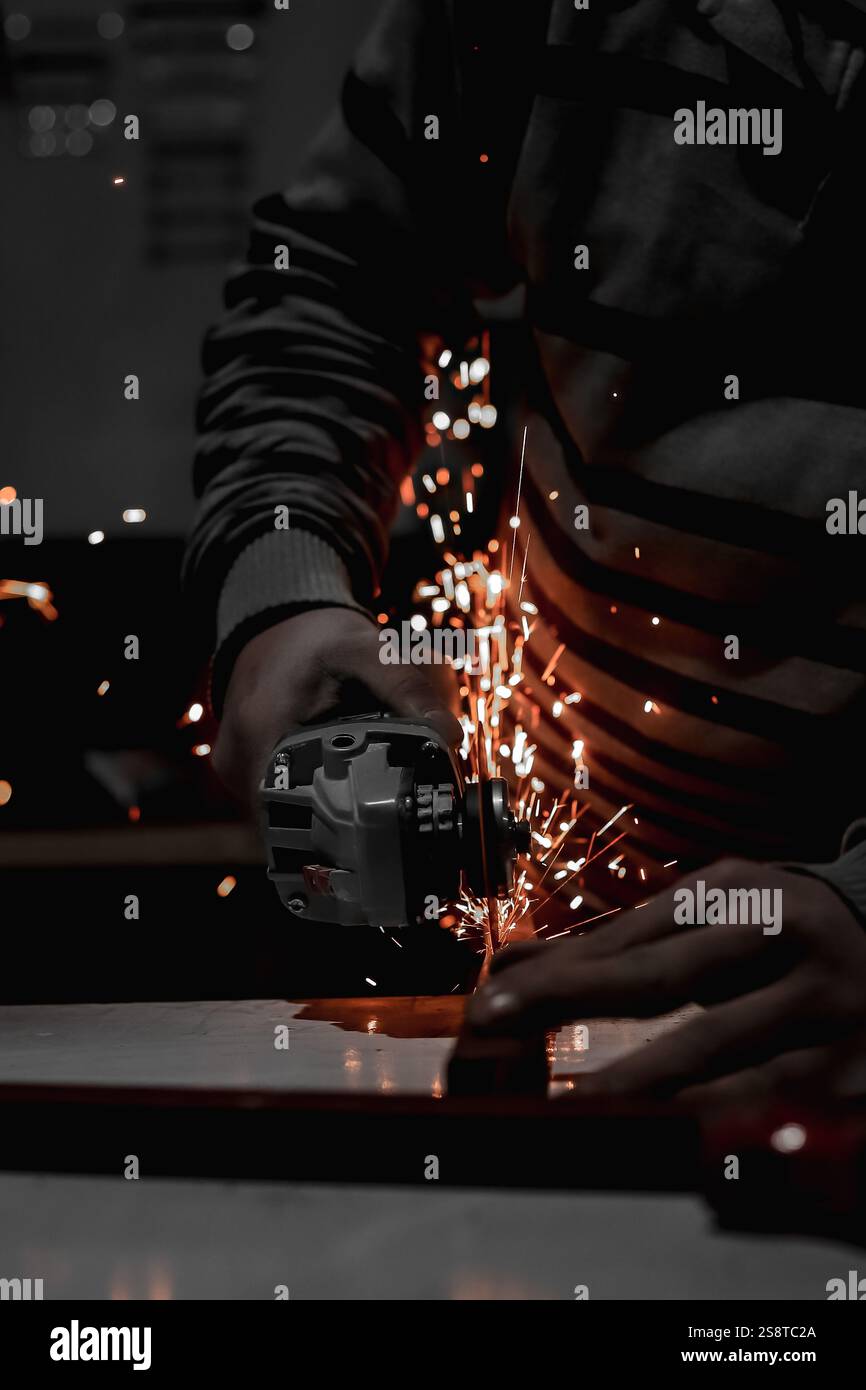 Welding sparks flying from metal as worker fuses steel with intense ...