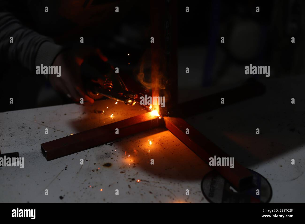 Welding sparks flying from metal as worker fuses steel with intense ...