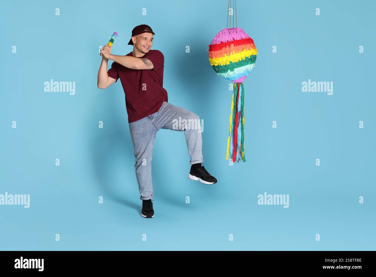 Happy man breaking pinata on light blue background Stock Photo - Alamy