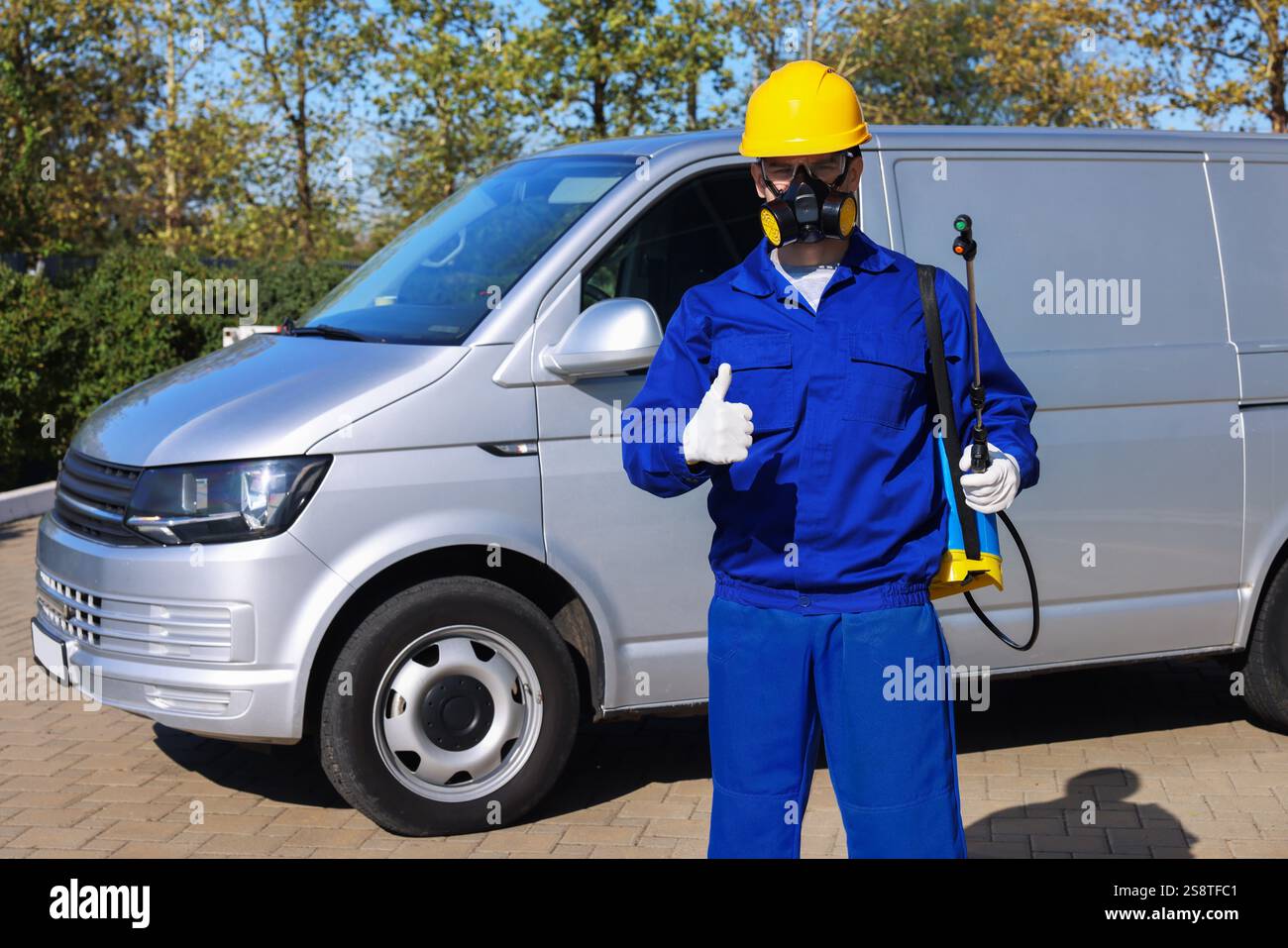 Pest control worker with spray tank showing thumbs up outdoors Stock ...
