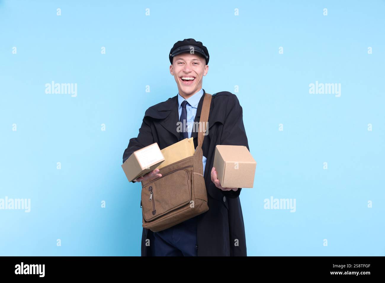 Happy postman with bag giving parcels on light blue background Stock ...