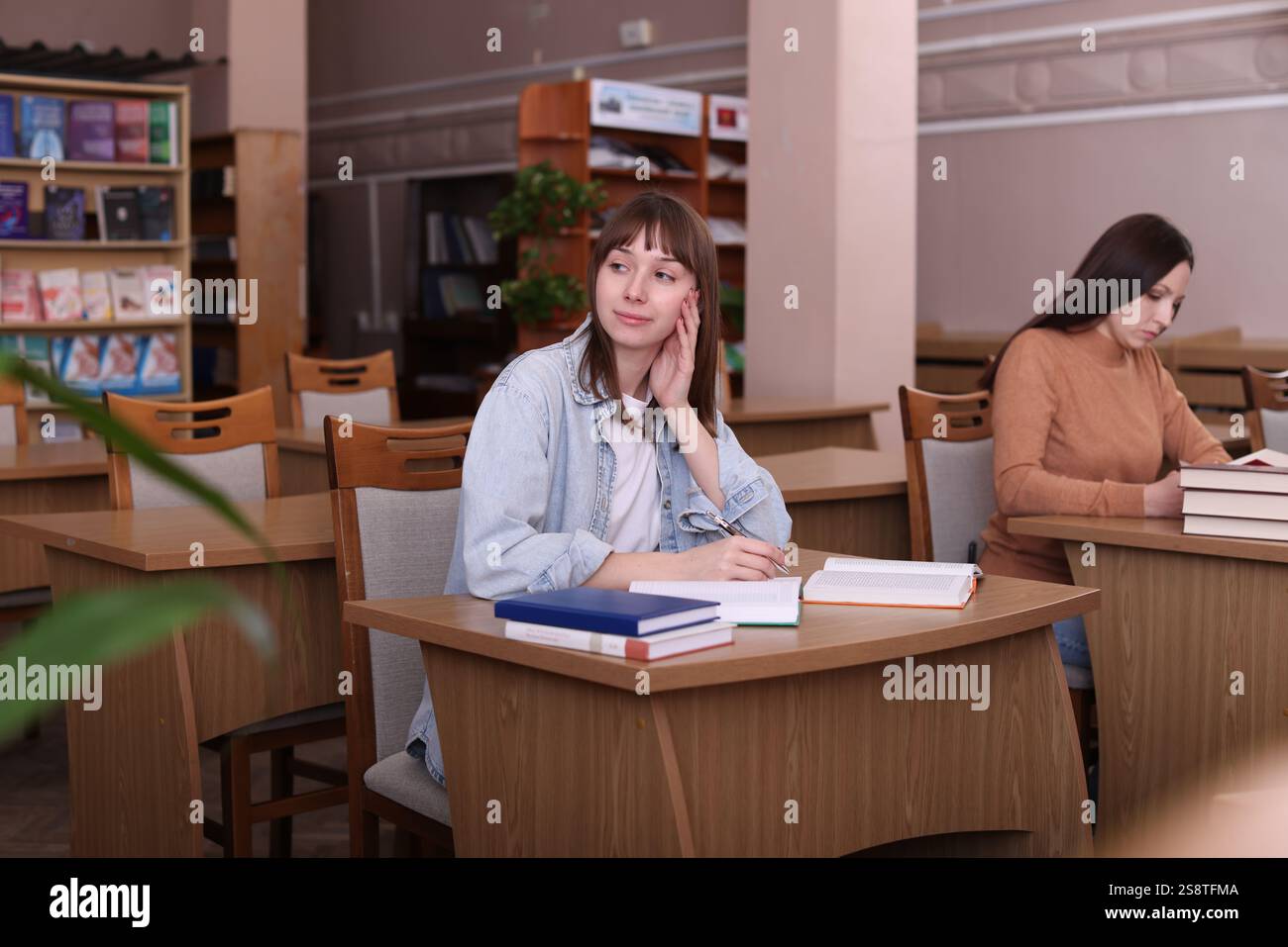 Beautiful women with books at desks in public library Stock Photo - Alamy