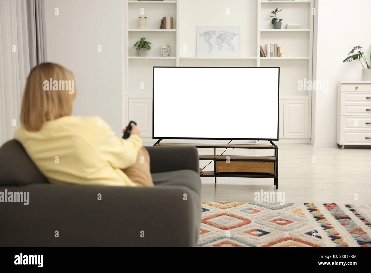 Woman watching TV on sofa at home, back view Stock Photo - Alamy