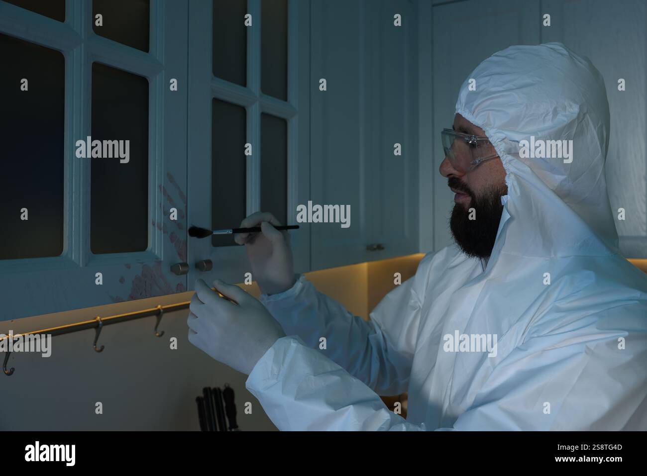 Forensic expert taking fingerprints from cupboard with brush at crime ...