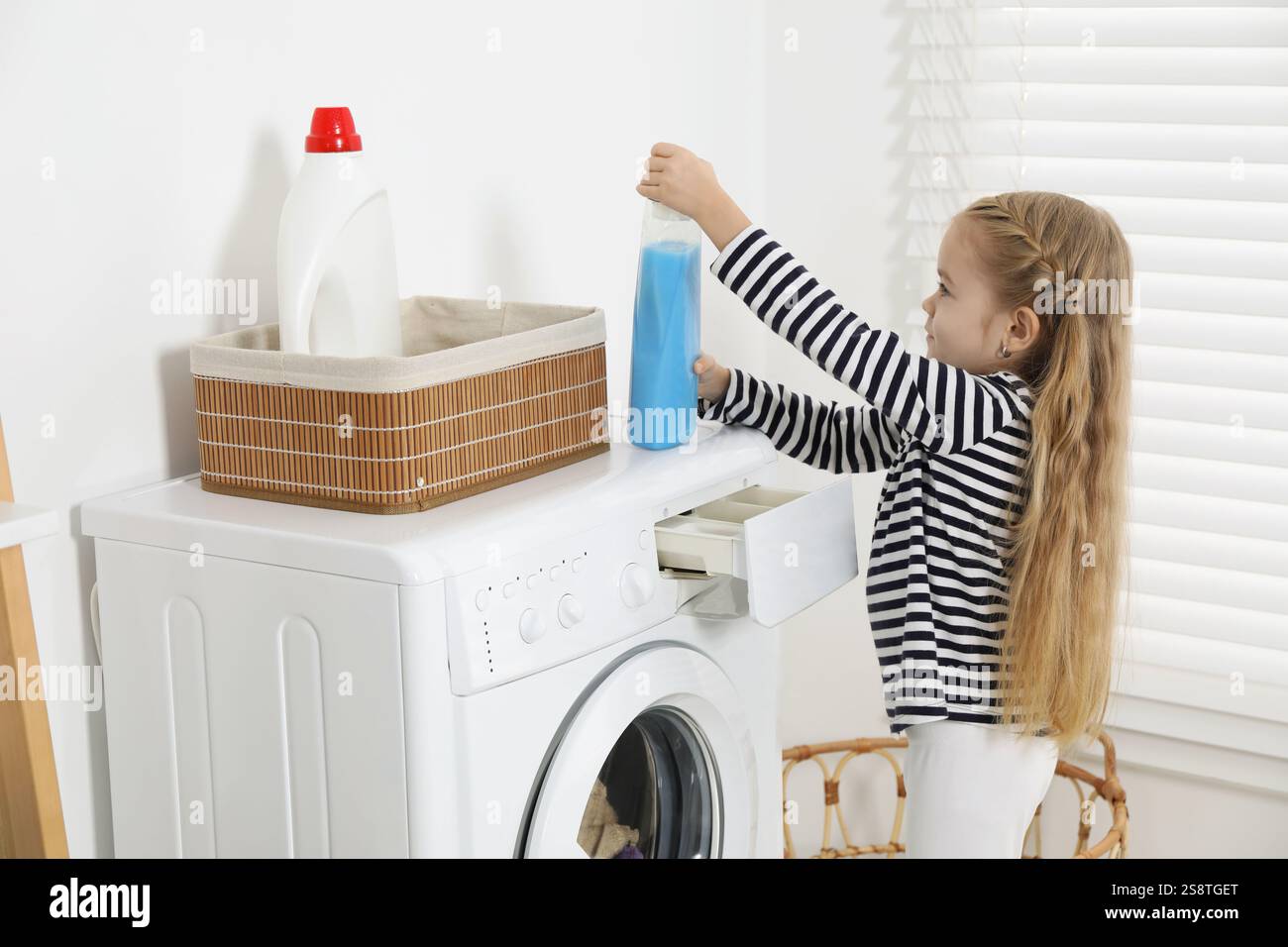 Little helper. Cute girl doing laundry at home Stock Photo - Alamy