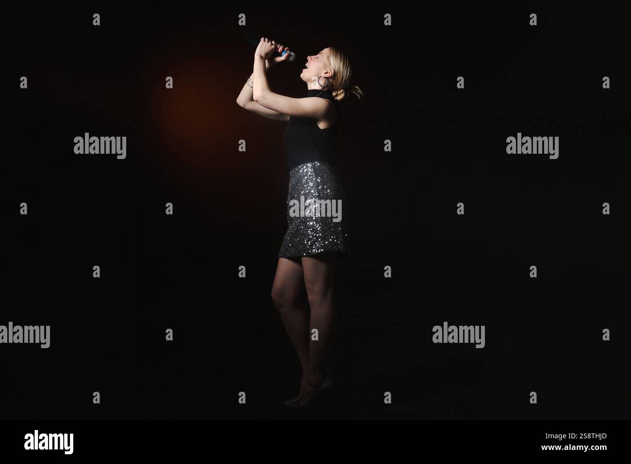 Beautiful singer performing on dark background with color light Stock ...