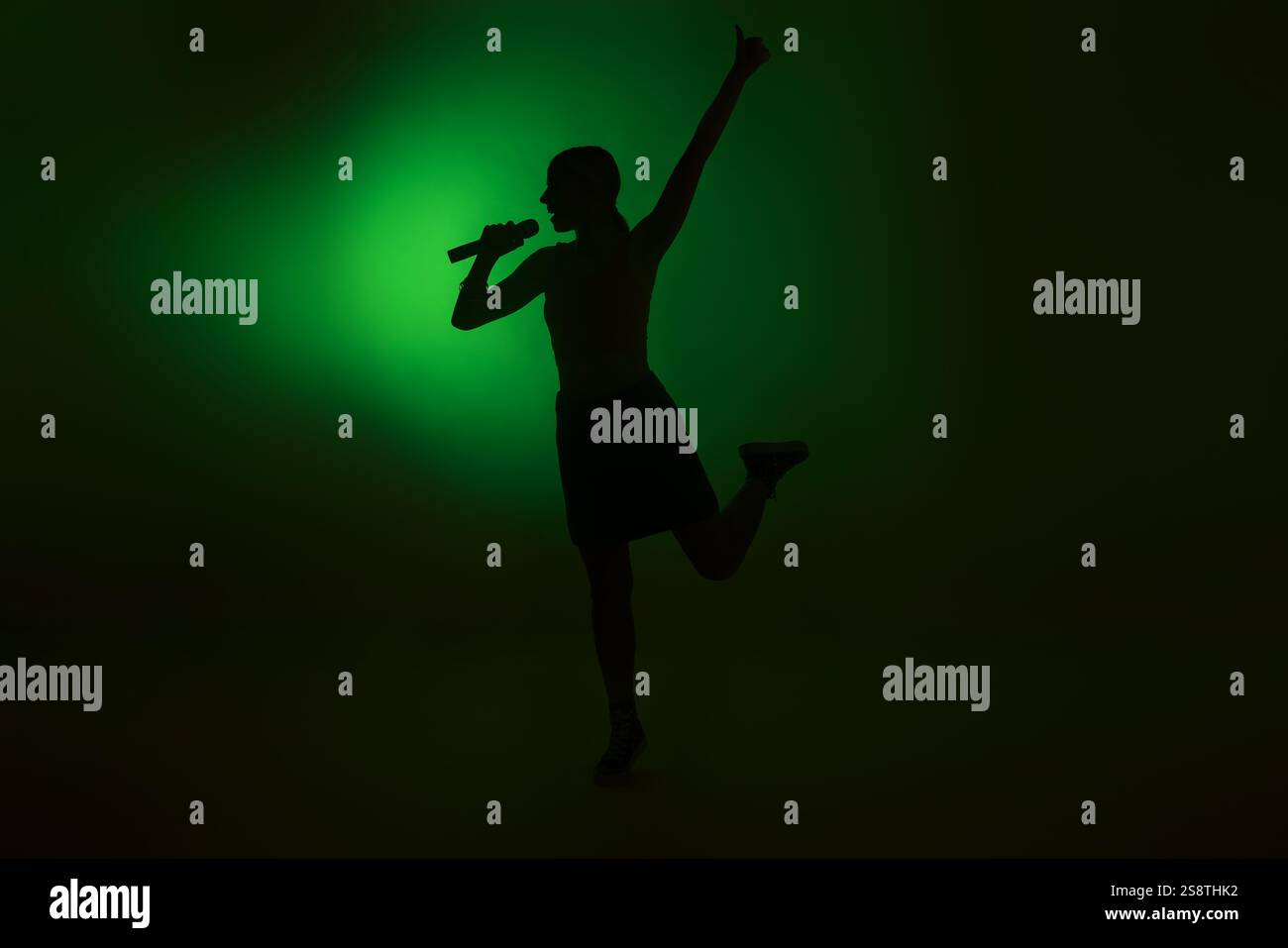 Silhouette of woman singing on dark background with green light Stock ...