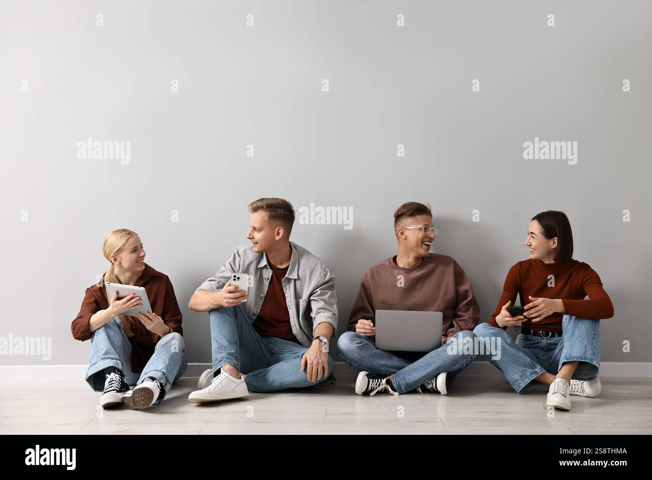 Group of people using different gadgets near light grey wall indoors ...