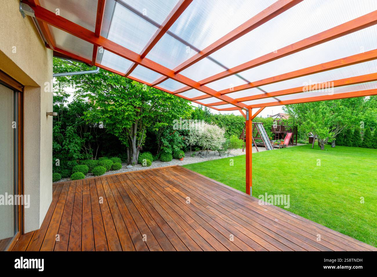 Wooden pergola with transparent polycarbonate roof covering a garden ...