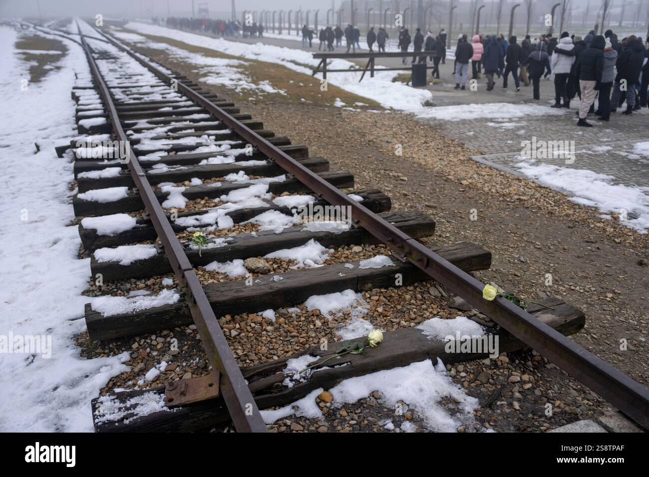 Visitors walk alongside the railroad tracks once used to transport Jews ...