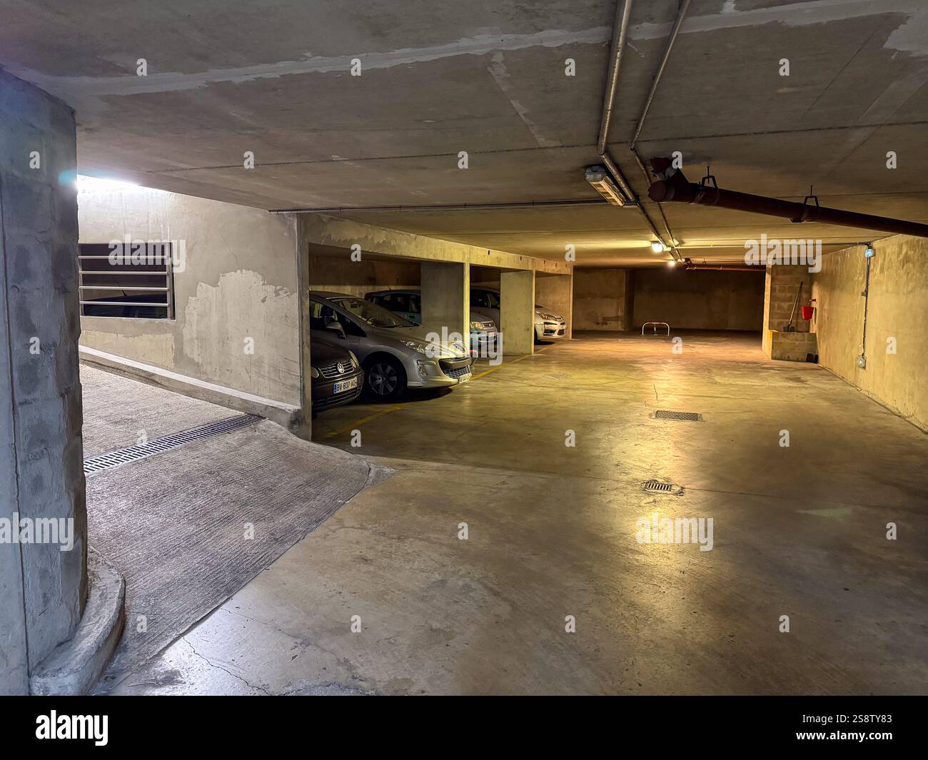 Empty underground parking garage with dim lighting and concrete walls ...
