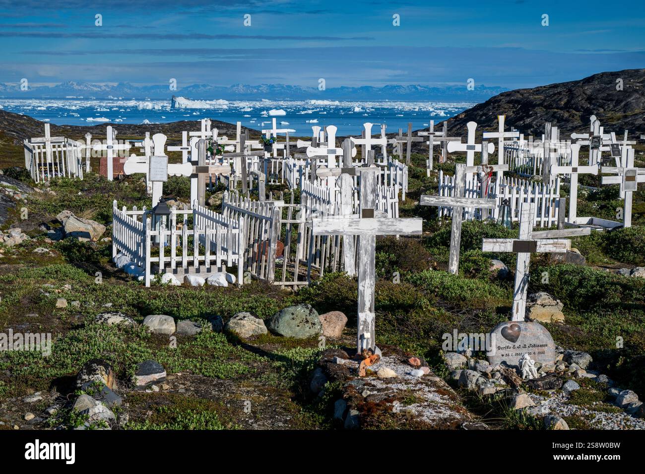 Colorful graves with white crosses are surrounded by lush summer ...