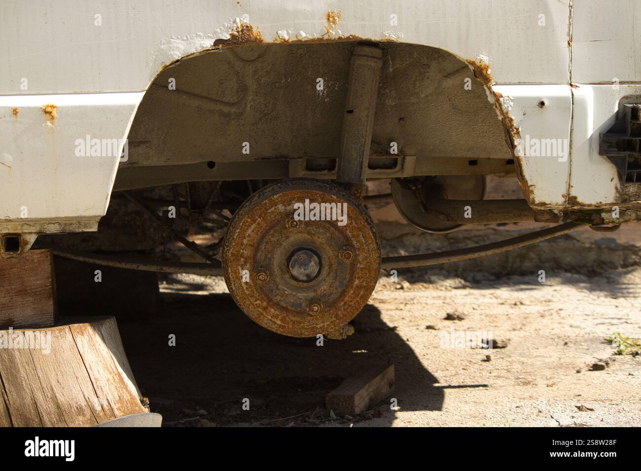 A close-up view of a vehicle's rear section, showing a rusted drum ...