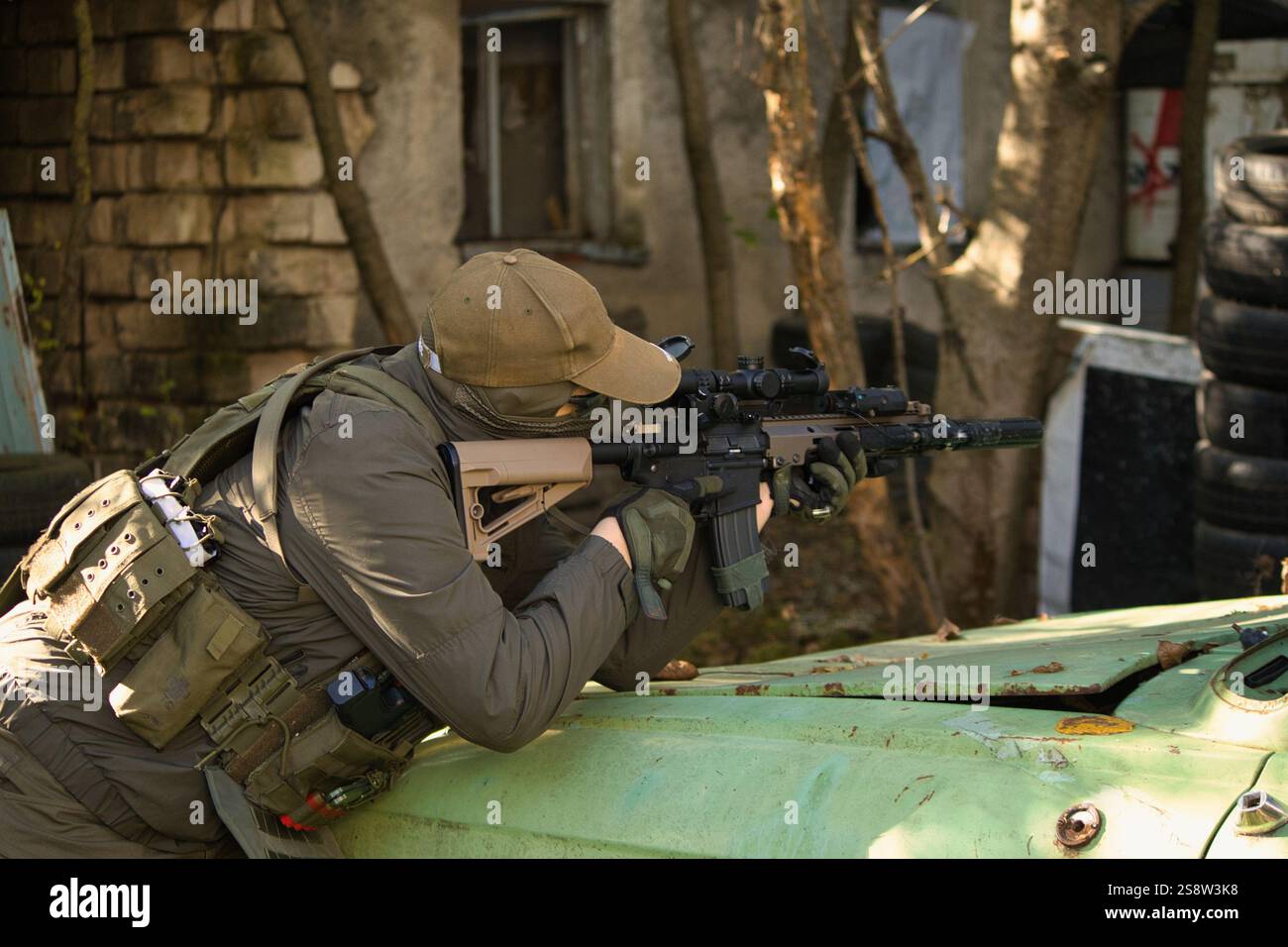A tactical operator dressed in full military gear takes a knee behind ...