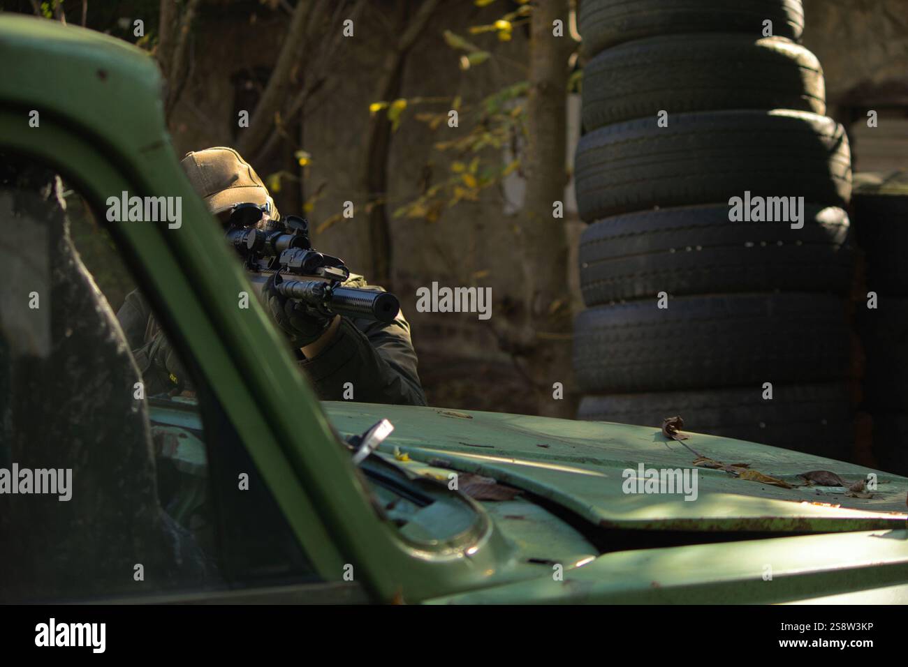 A tactical operator dressed in full military gear takes a knee behind ...