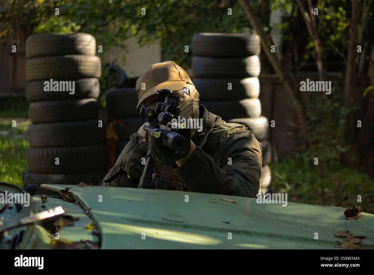 A tactical operator dressed in full military gear takes a knee behind ...
